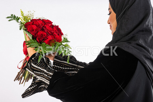 Portrait of a Saudi Arabian Gulf woman holding a beautiful red rose ...