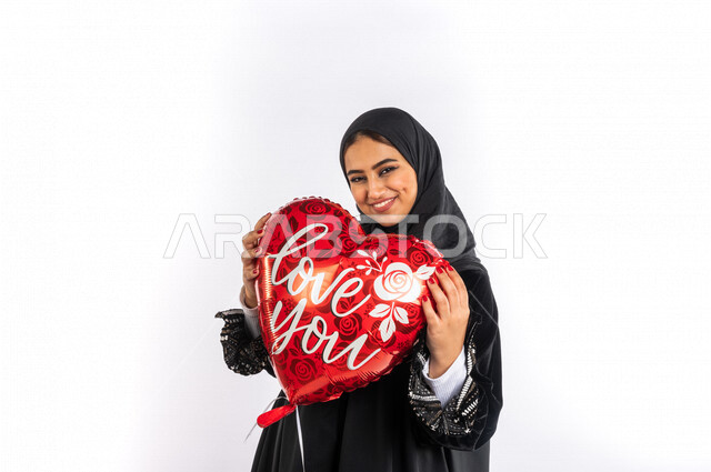 Portrait of a Saudi Arabian Gulf woman holding a red helium balloon in ...
