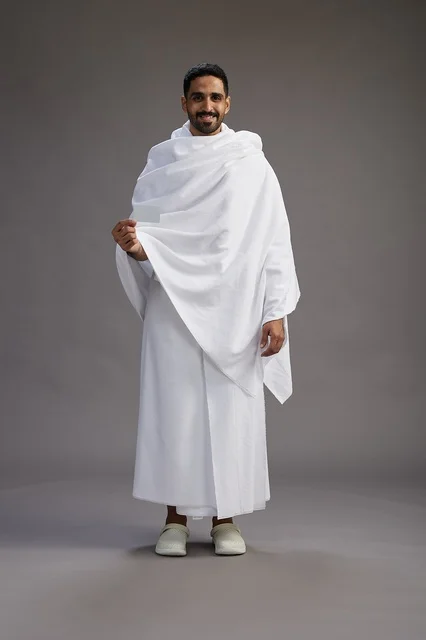 A portrait of a Saudi man in Ihram clothing holding a blank white card ...