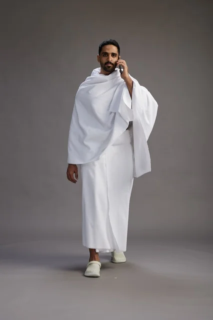 A portrait of a Saudi man in Ihram clothing making a phone call on a ...