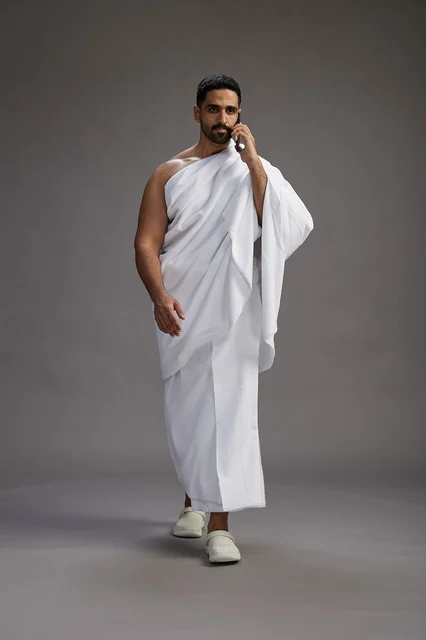 A portrait of a Saudi man in Ihram clothing making a phone call on a ...