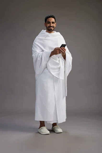 A portrait of an Arab Saudi Gulf man wearing Ihram clothing using a ...
