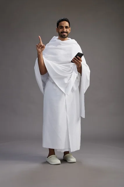 A portrait of an Arab Saudi Gulf man wearing Ihram clothing using a ...