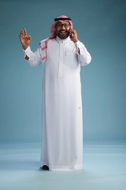 A portrait of a Saudi man wearing a white thobe and a shemagh, talking ...