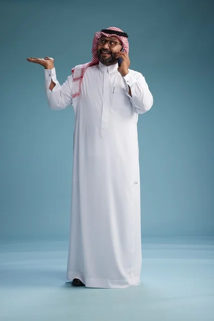 A portrait of a Saudi man wearing a white thobe and a shemagh, talking ...
