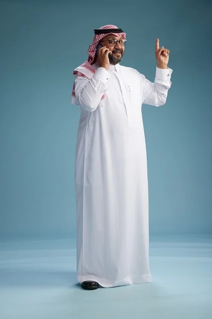 A portrait of a Saudi man wearing a white thobe and a shemagh, talking ...
