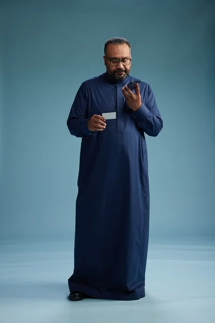 A portrait of a Saudi man using a mobile phone sitting on a chair while ...