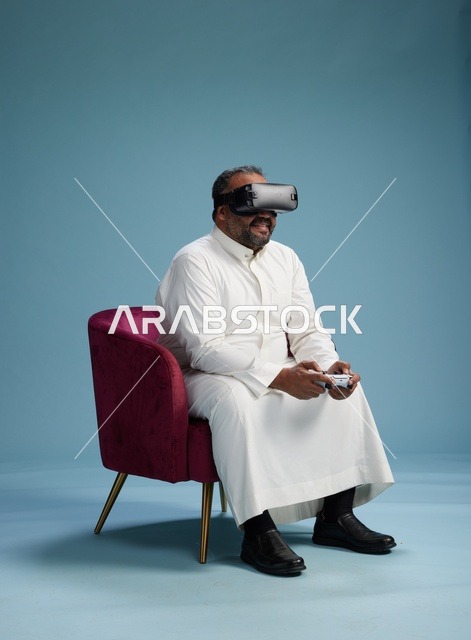 A portrait of a Saudi man wearing virtual reality glasses and holding a ...