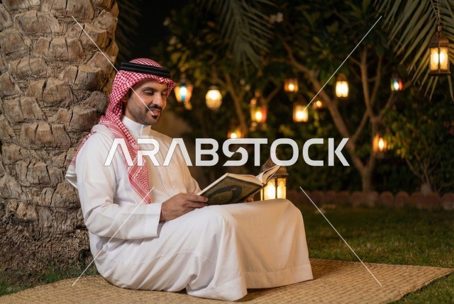 A Saudi Arabian Gulf man wearing traditional attire and a shemagh reads ...