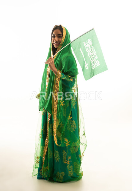 Saudi Woman in Traditional Green Dress Holding Flag - Photo