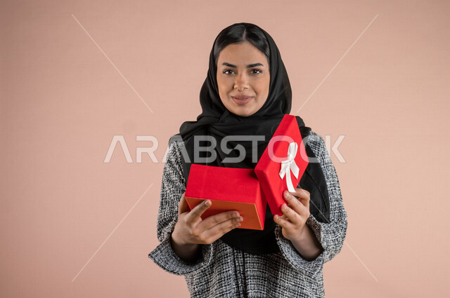 Portrait of a Saudi Arabian Gulf woman holding a red box in her hand, a ...
