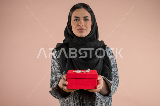 Portrait of a Saudi Arabian Gulf woman holding a red box in her hand, a ...