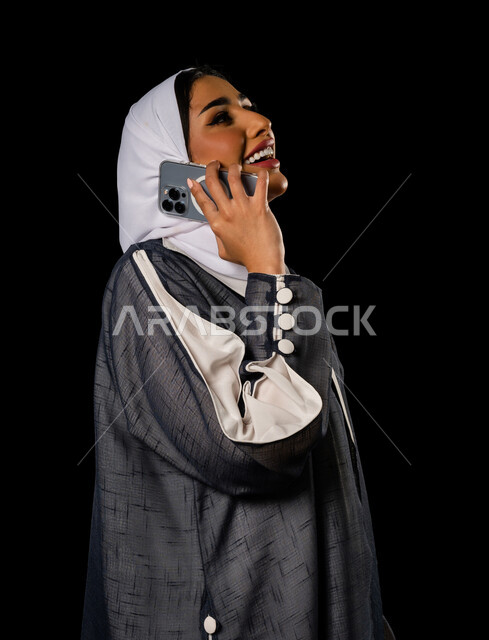 Portrait of a smiling Saudi Arabian Gulf woman with a mobile phone in ...