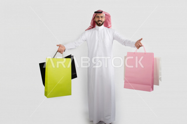 Portrait of a Saudi Arabian man carrying a set of colorful shopping ...