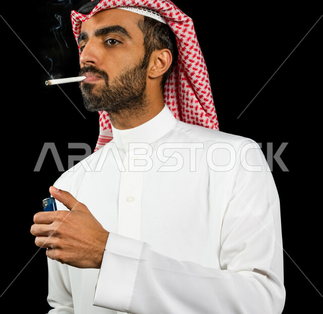 A Saudi Arabian Gulf man wearing a Saudi dress smoking cigarettes ...
