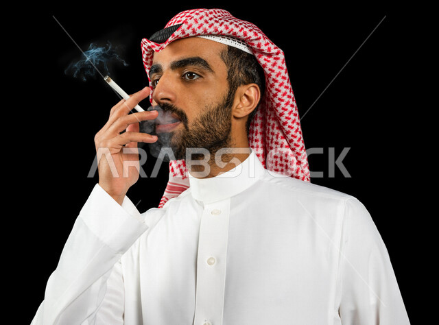 A Saudi Arabian Gulf man wearing a Saudi dress smoking cigarettes ...