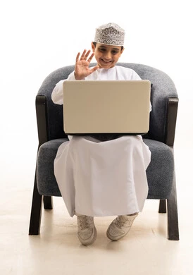 Omani Boy in Traditional Dress Using Laptop - Photo