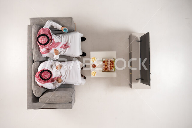 Saudi Men Watching TV with Pizza and Popcorn Overhead - Photo
