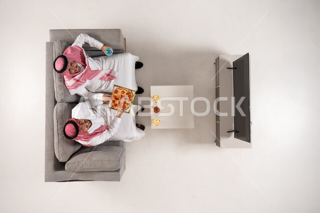 Saudi Men Eating Pizza Watching TV Top View - Photo