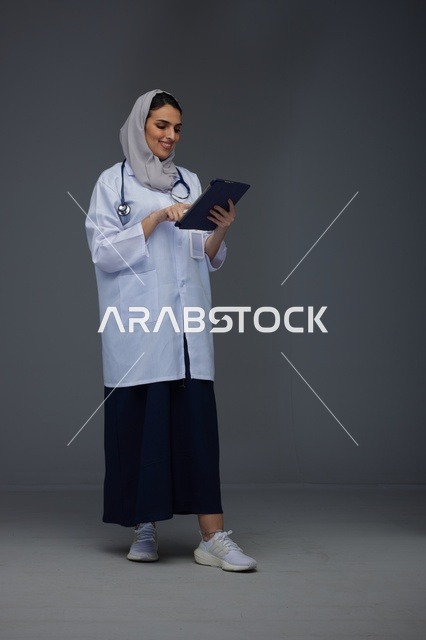 Saudi Female Doctor Using Tablet in Medical Uniform - Photo