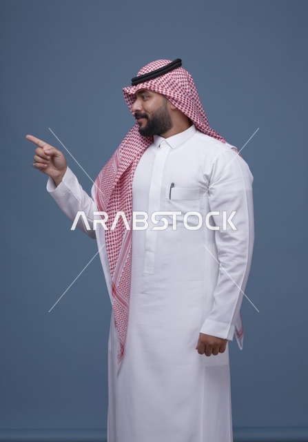 Saudi Man in Traditional Dress Pointing Side in Studio - Photo