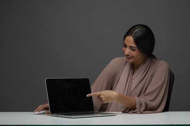 Saudi Woman Pointing at Laptop Screen in Studio - Photo