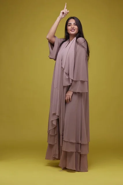 Saudi Woman in Abaya Pointing Up on Yellow Background - Photo