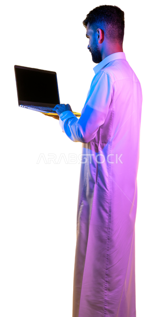 Portrait of a Saudi Arabian Gulf youth holding a laptop in his hand ...