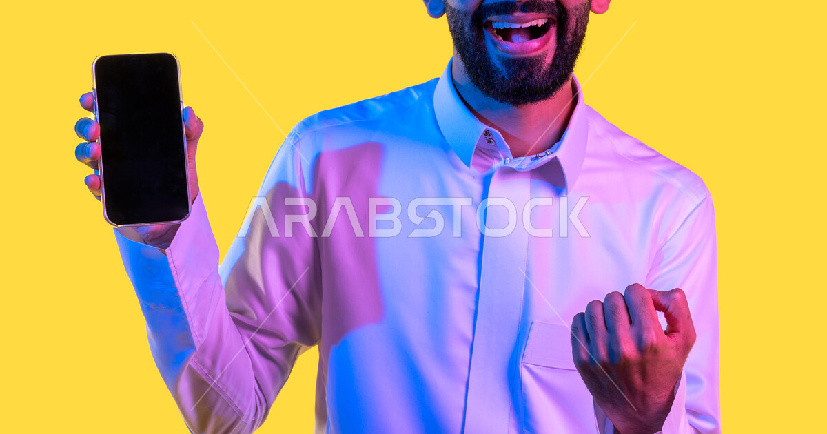 Portrait of a Saudi Arabian Gulf youth displaying a mobile phone device ...