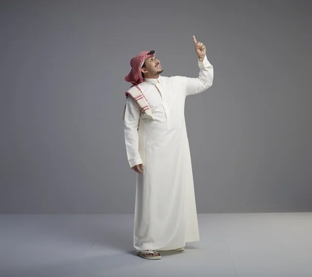 رجل سعودي بالزي التقليدي يشير بيده في الاستوديو - صورة