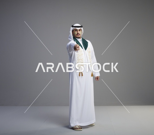 رجل سعودي بالزي التقليدي يشير بيده في الاستوديو - صورة