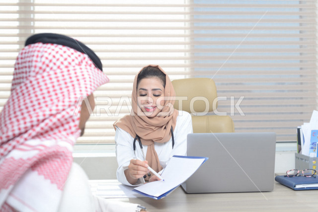 A Saudi Arabian Gulf doctor wearing a medical coat and sitting in her ...