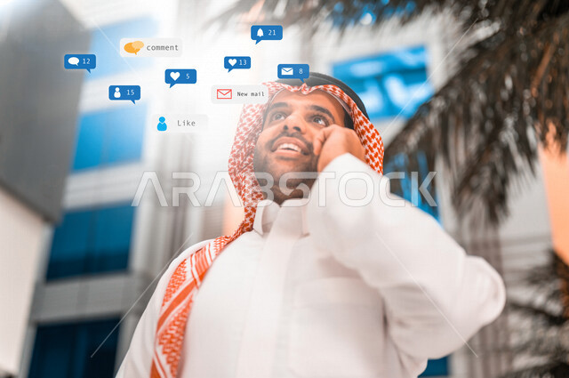 A Saudi Arabian Gulf man makes a call through a mobile phone and looks ...