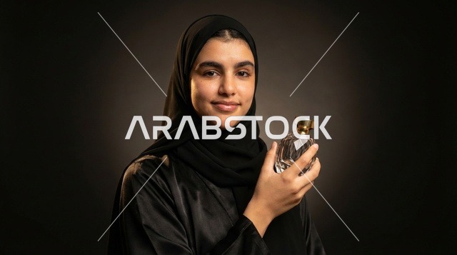 Saudi Woman in Black Abaya Holding Perfume Bottle - Photo