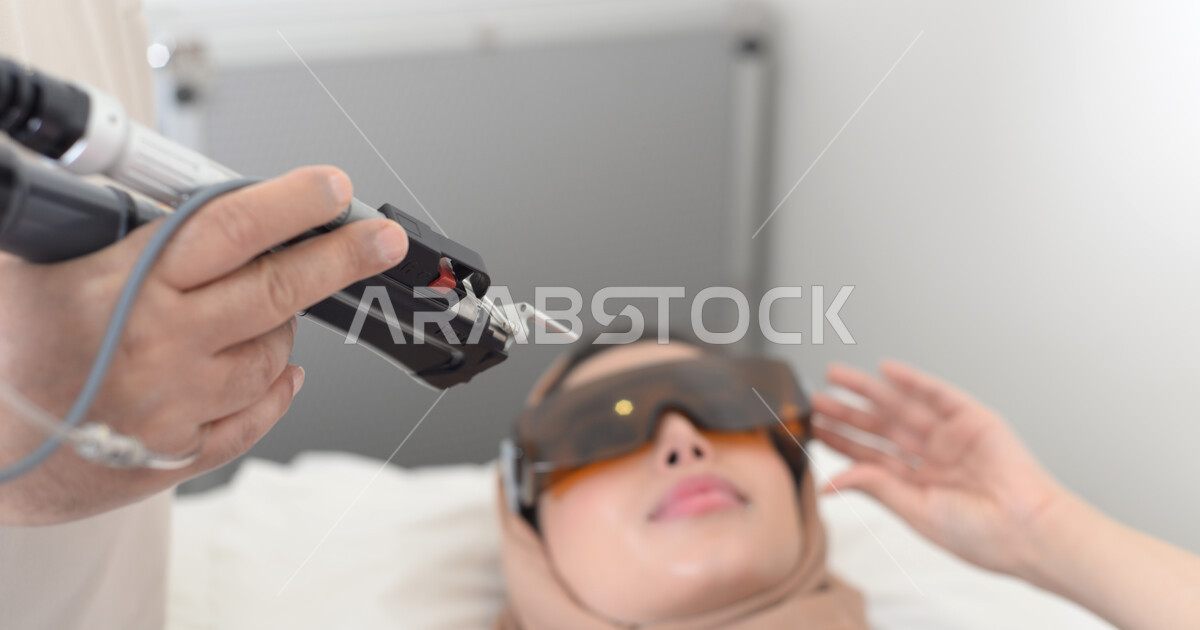 A Saudi Gulf Arab doctor uses a laser device on the face of a Saudi ...