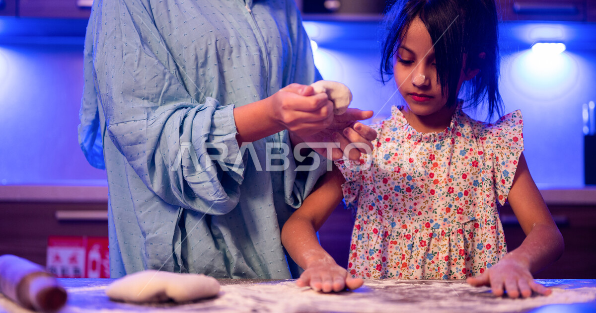 A Saudi Arabian Gulf mother with her daughter in the kitchen, teaching ...
