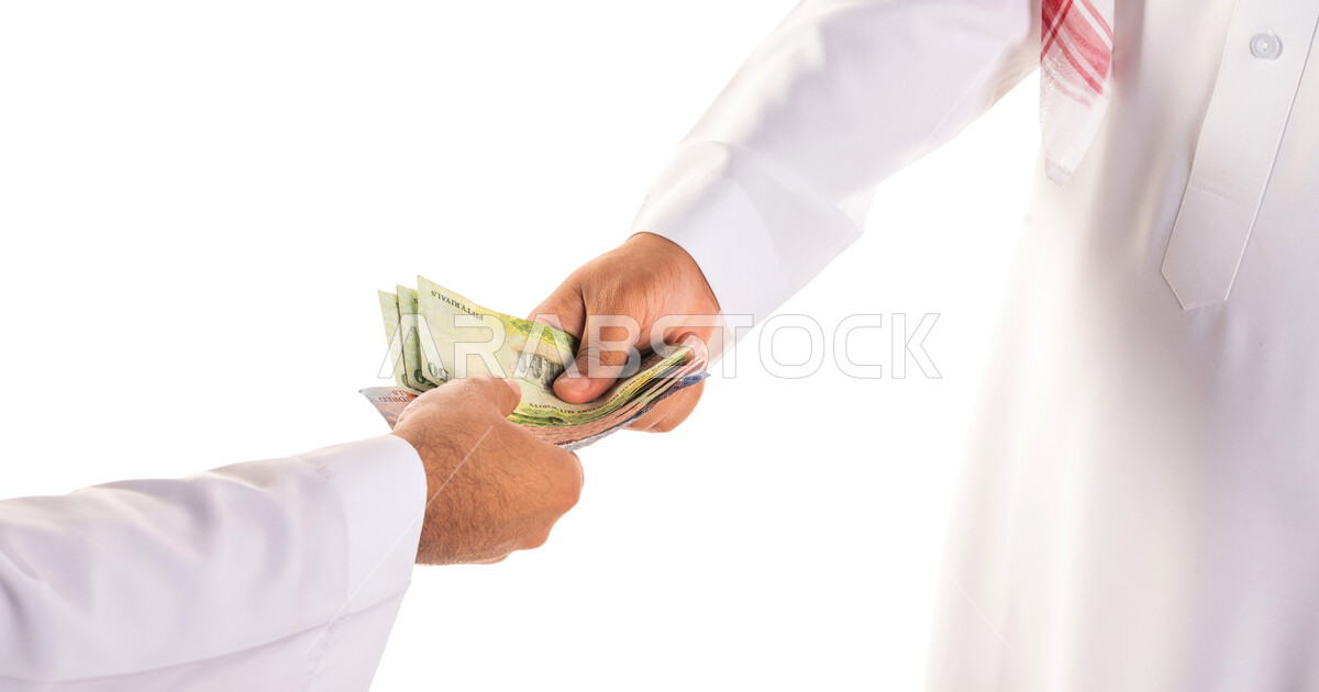 Portrait of a Saudi Arabian Gulf man giving paper money to a Gulf man ...