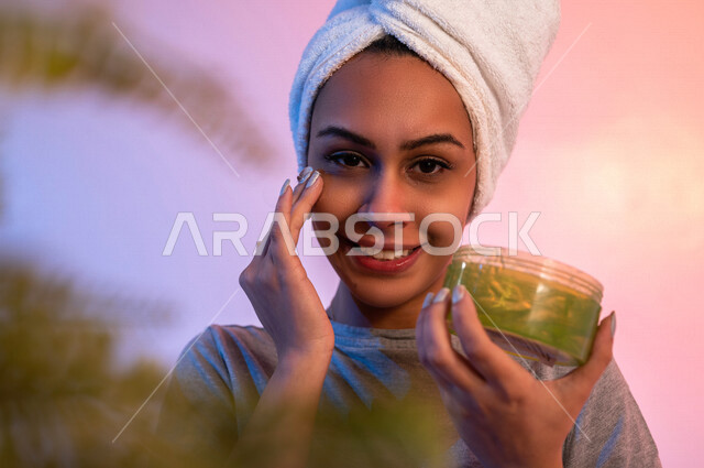 Portrait of a smiling Saudi Arabian Gulf woman, holding in her hand a ...