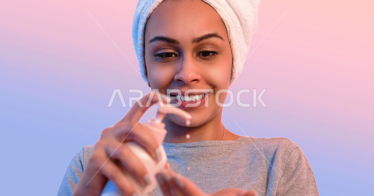 Portrait of a Saudi Arabian Gulf woman, putting a moisturizing cream on ...