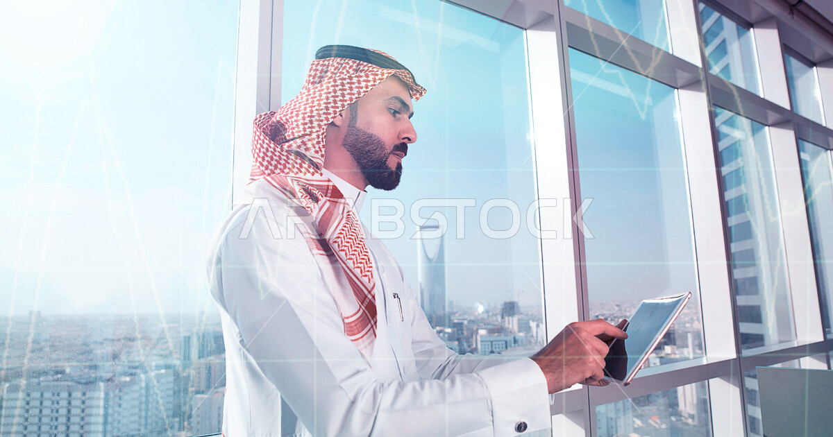 A Saudi Arabian Gulf businessman uses a tablet device to follow the ...