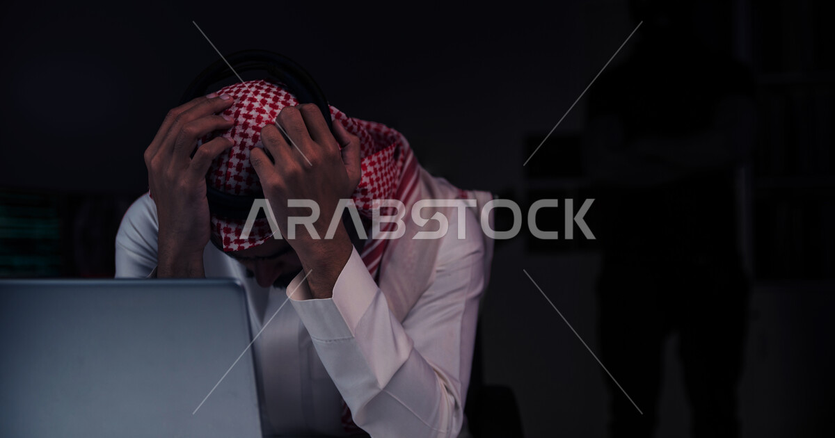 A Saudi Arabian Gulf man sitting in front of the laptop with gestures ...