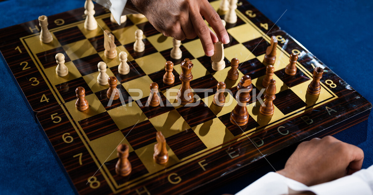 A close-up of two Saudi Arabian Gulf youths playing chess, the concept ...