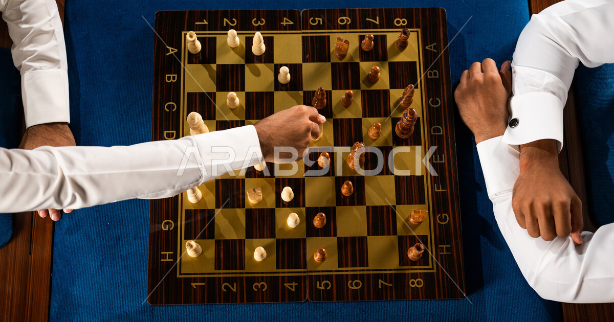 A close-up of two Saudi Arabian Gulf youths playing chess, the concept ...