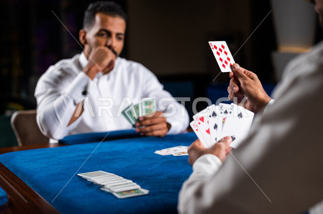 A close-up of two Saudi Arabian Gulf youths playing a game of cards ...
