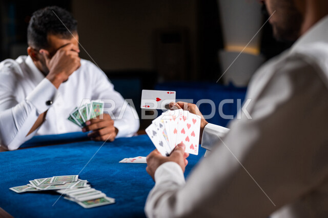 A close-up of two Saudi Arabian Gulf youths playing a game of cards ...
