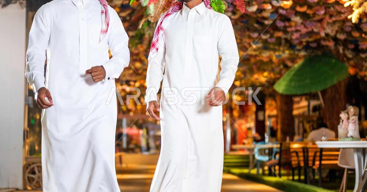 Two smiling Saudi Arabian Gulf Arab men walking together on an ...