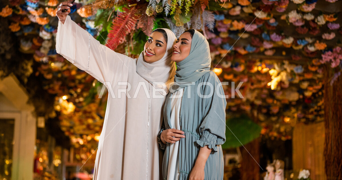Two Saudi Arabian Gulf women, two smiling friends, walking together on ...