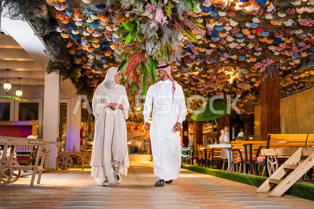 A smiling Saudi Arabian Gulf couple walking together on a fun outing to ...