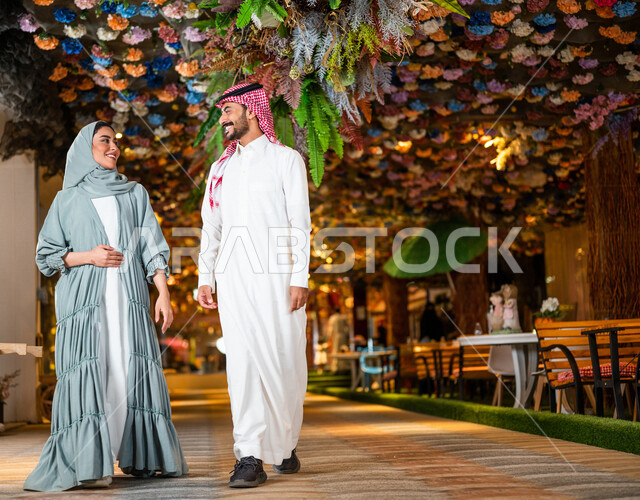A smiling Saudi Arabian Gulf couple walking together on a fun outing to ...
