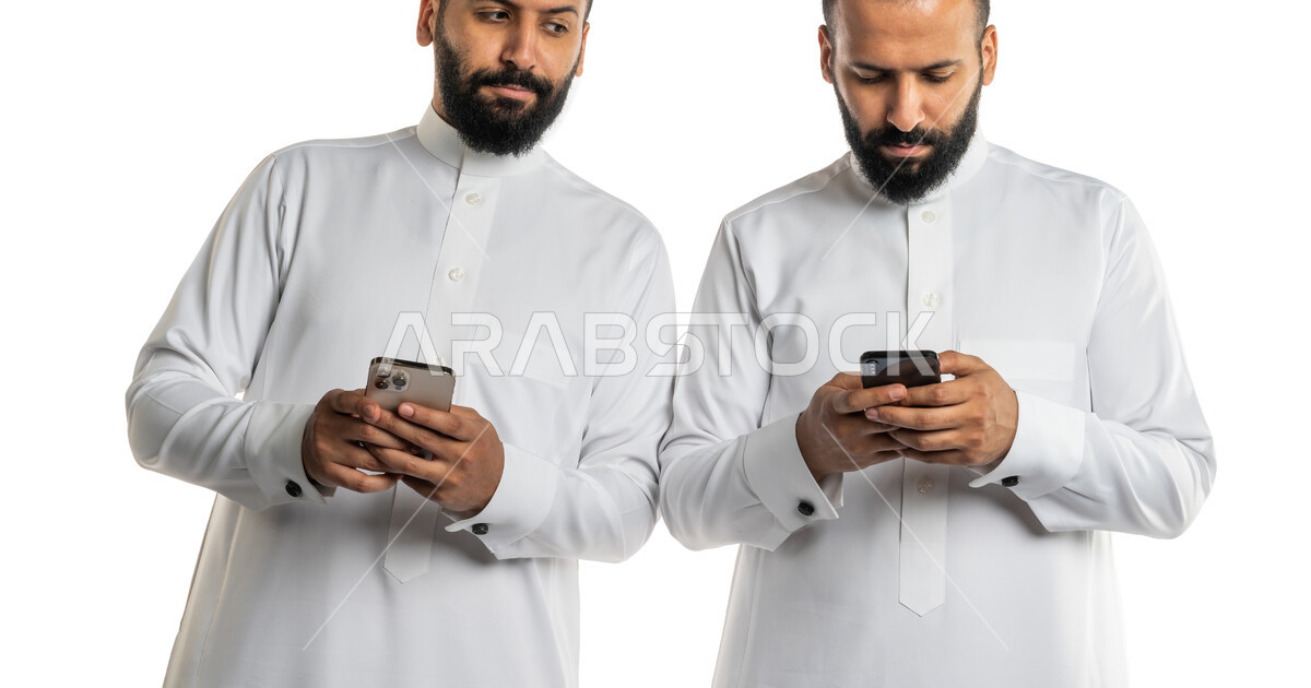 Portrait of two Saudi Arabian Gulf twin men using a mobile phone ...